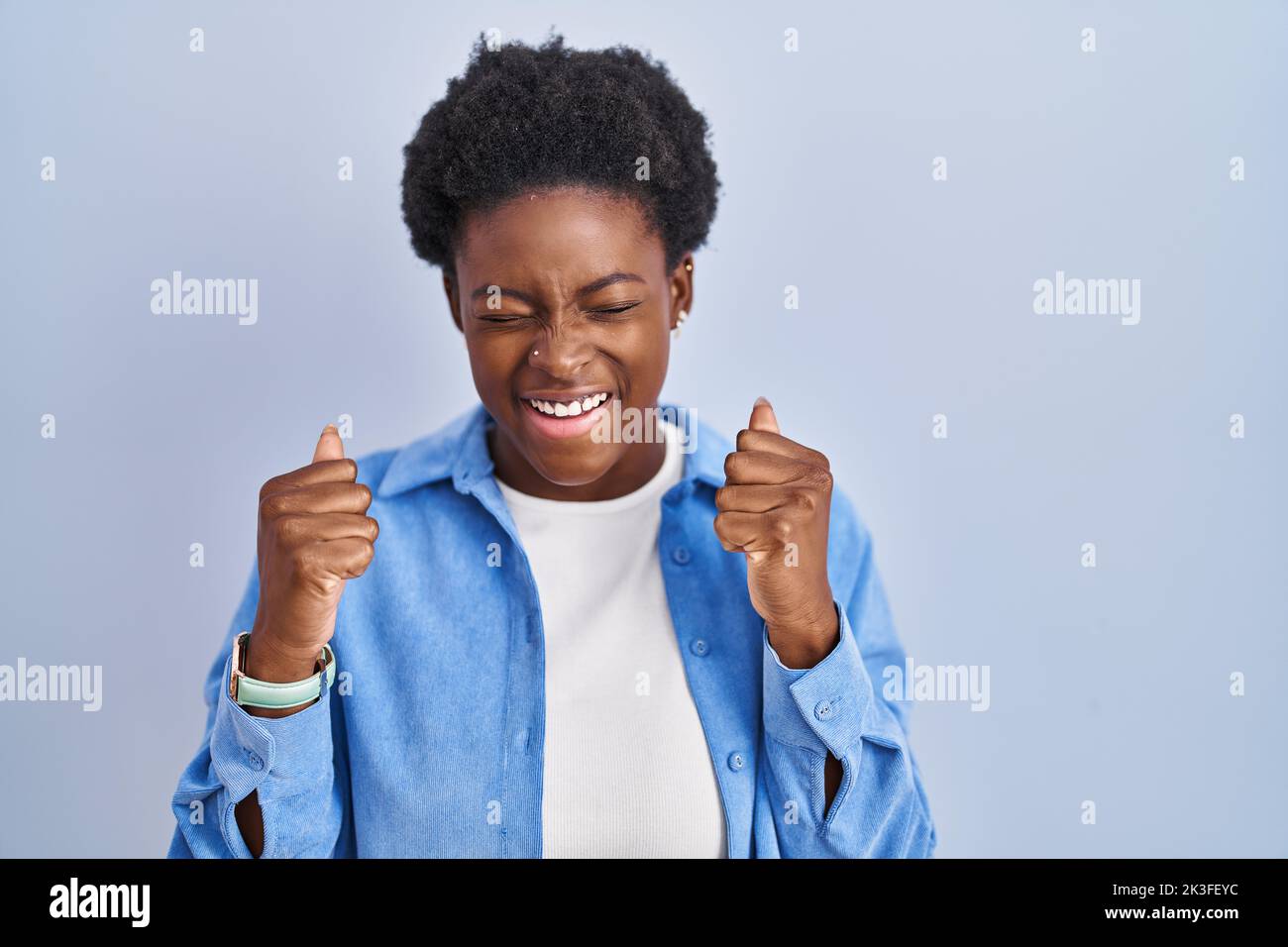 African american woman standing over blue background excited for ...