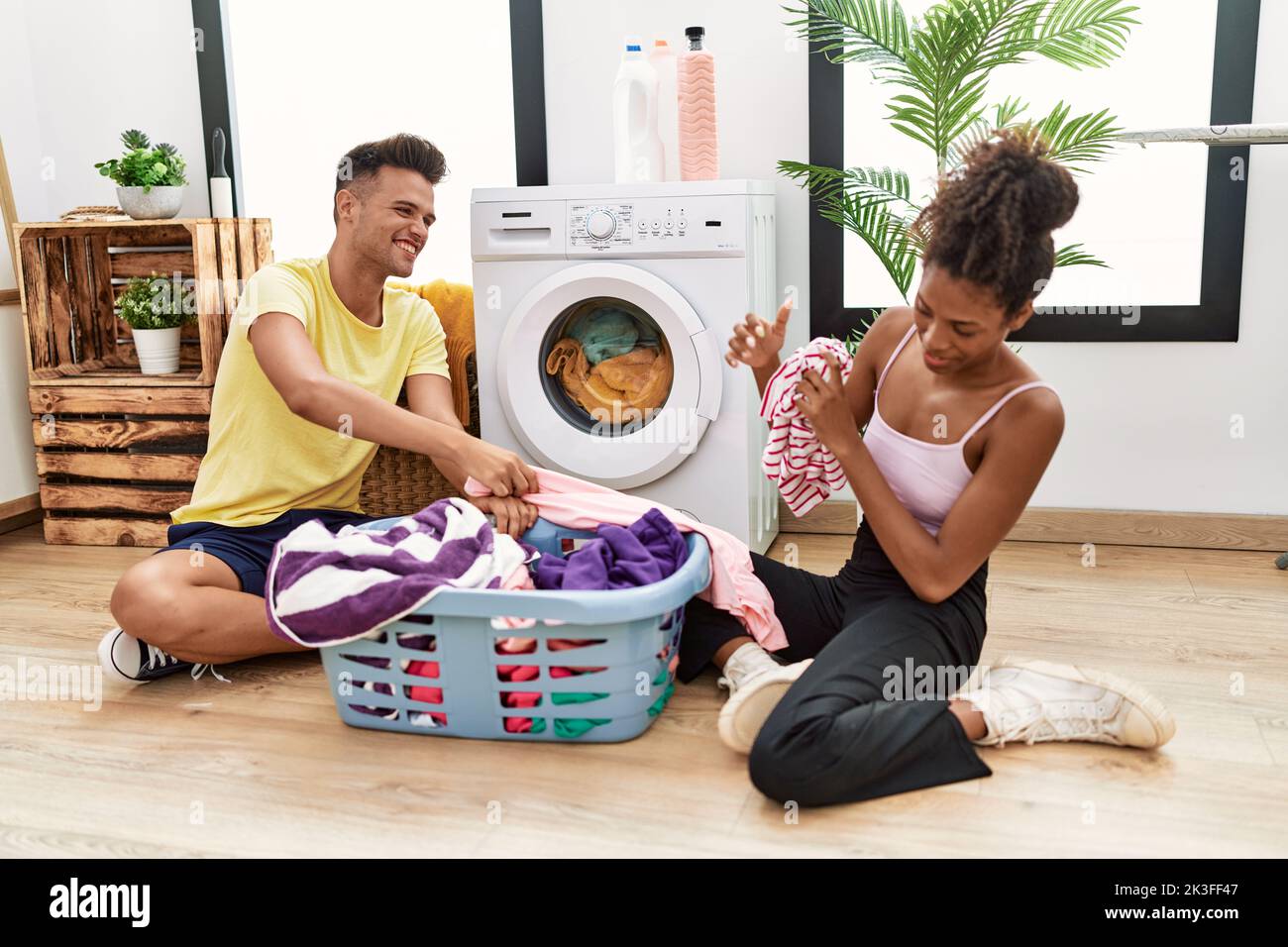 Man and woman couple playing throwing clothes at laundry room Stock ...