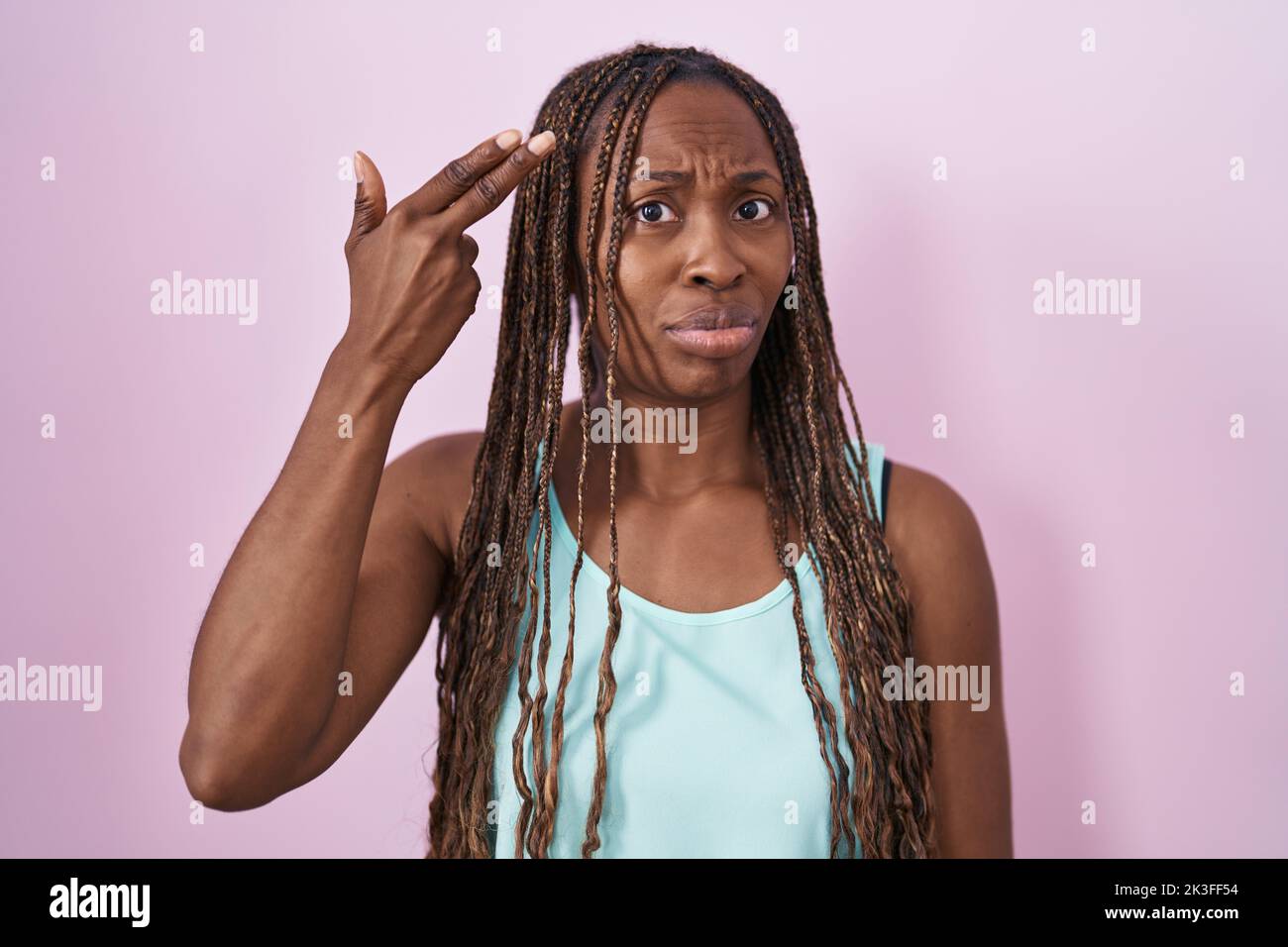 African american woman standing over pink background shooting and ...