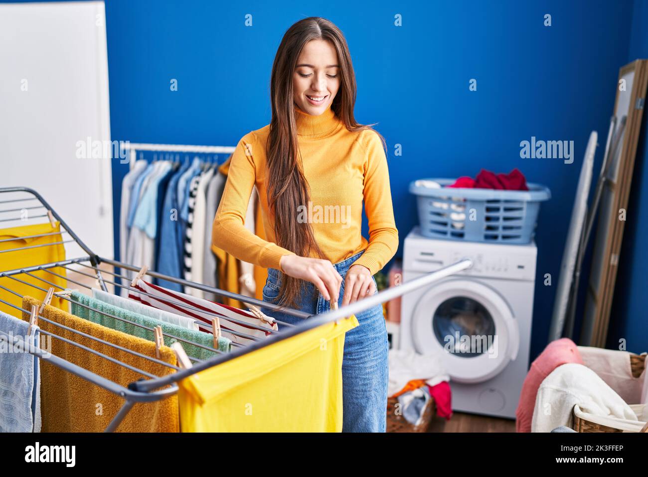 Young beautiful hispanic woman smiling confident hanging clothes on ...