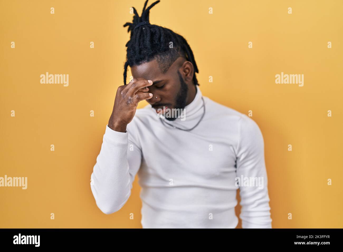African man with dreadlocks wearing turtleneck sweater over yellow ...
