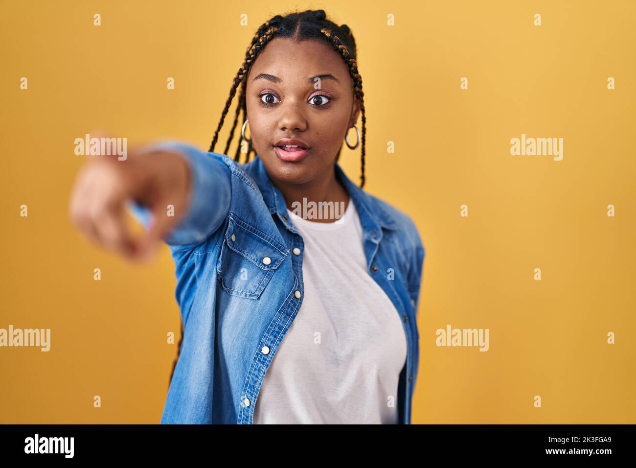African american woman with braids standing over yellow background ...