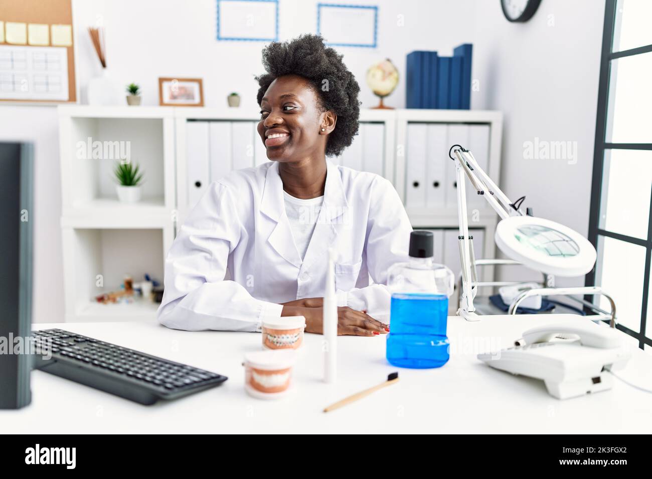 African dentist woman working at medical clinic looking away to side ...