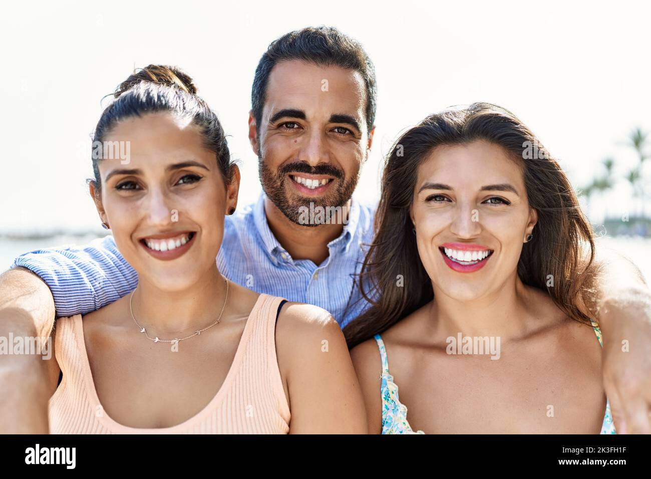 Three young hispanic friends smiling happy and hugging at the beach ...