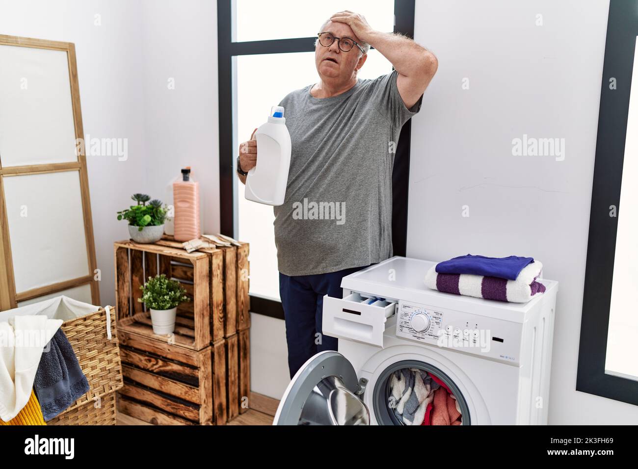 Senior caucasian man doing laundry holding detergent bottle stressed ...