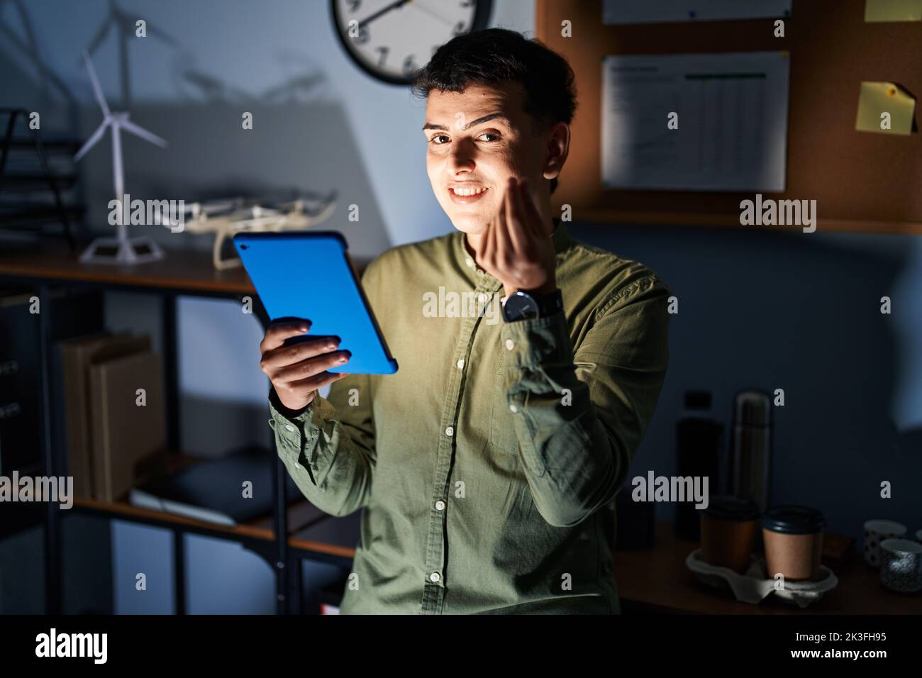 Non binary person using touchpad device at night doing money gesture ...