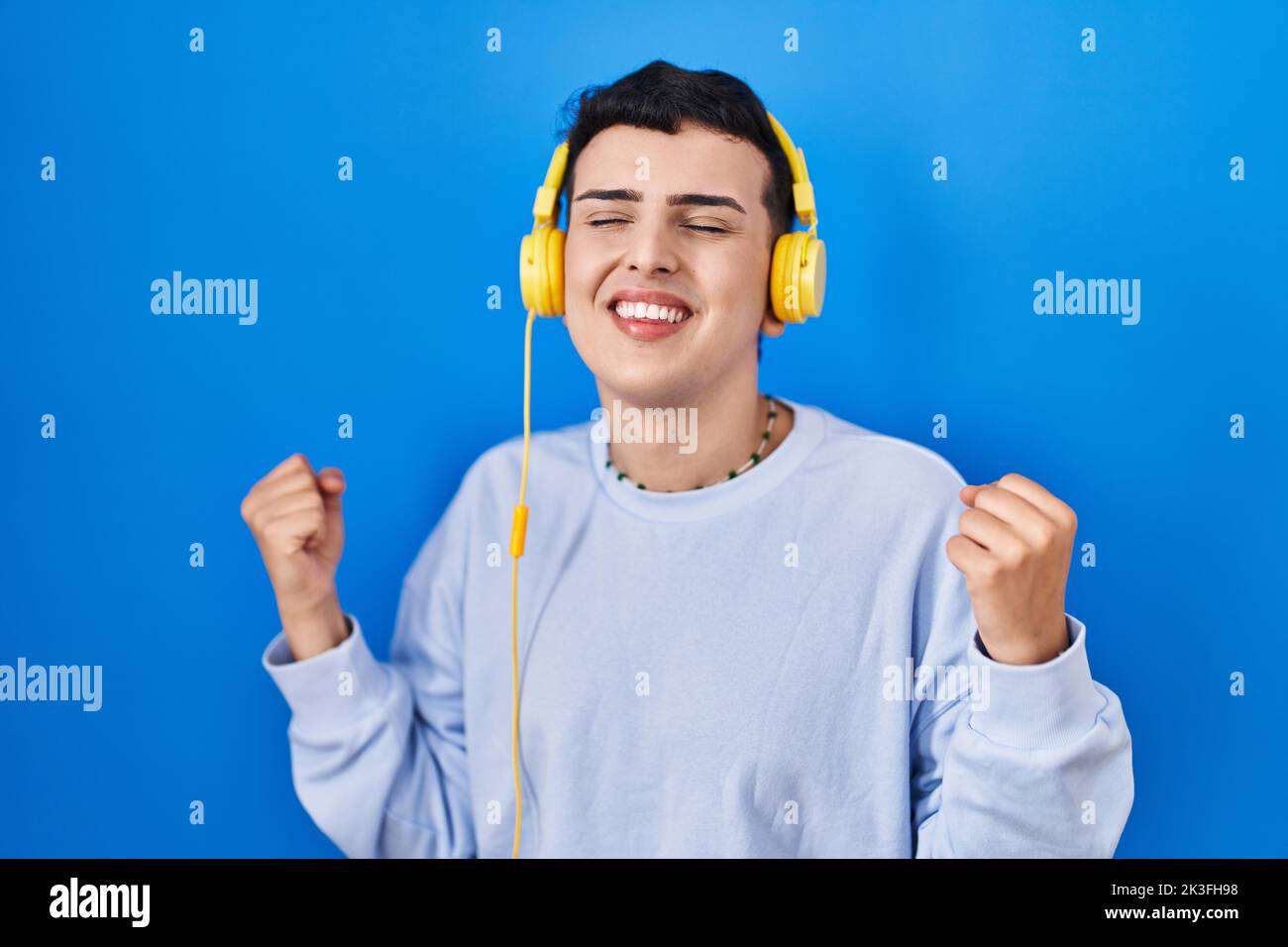 Non binary person listening to music using headphones celebrating ...