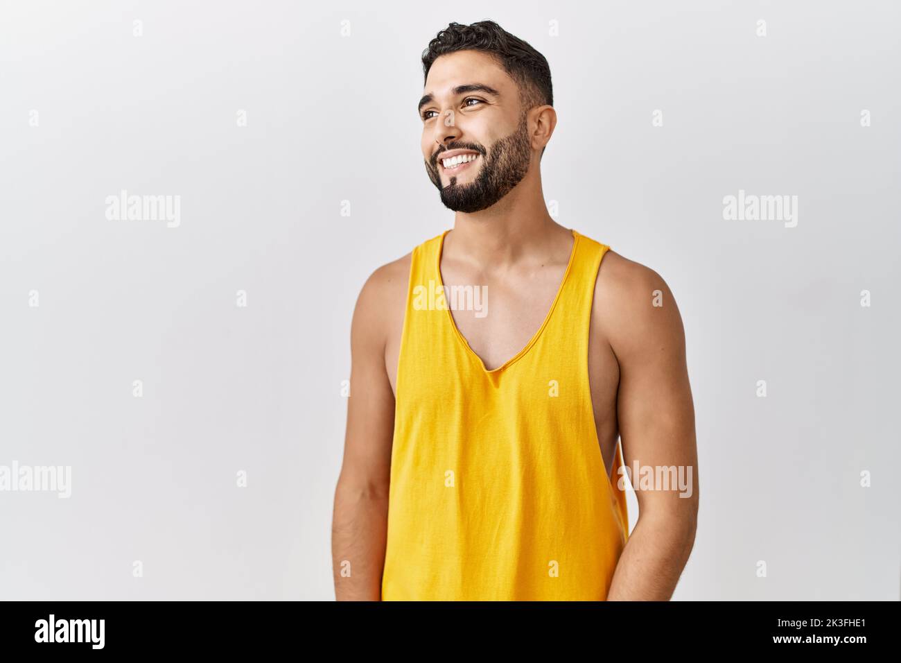 Young handsome man with beard standing over isolated background looking ...