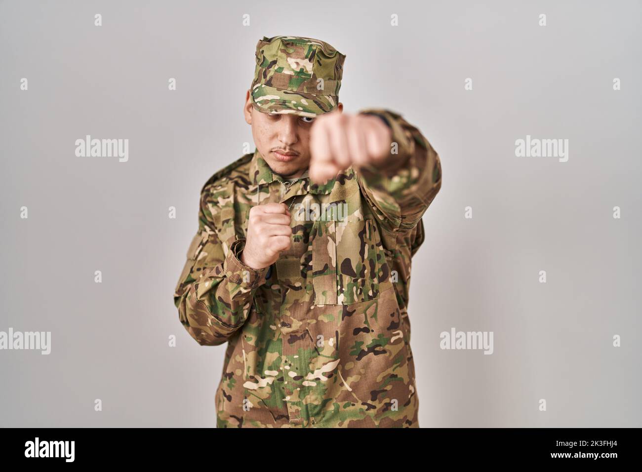 Young arab man wearing camouflage army uniform punching fist to fight ...