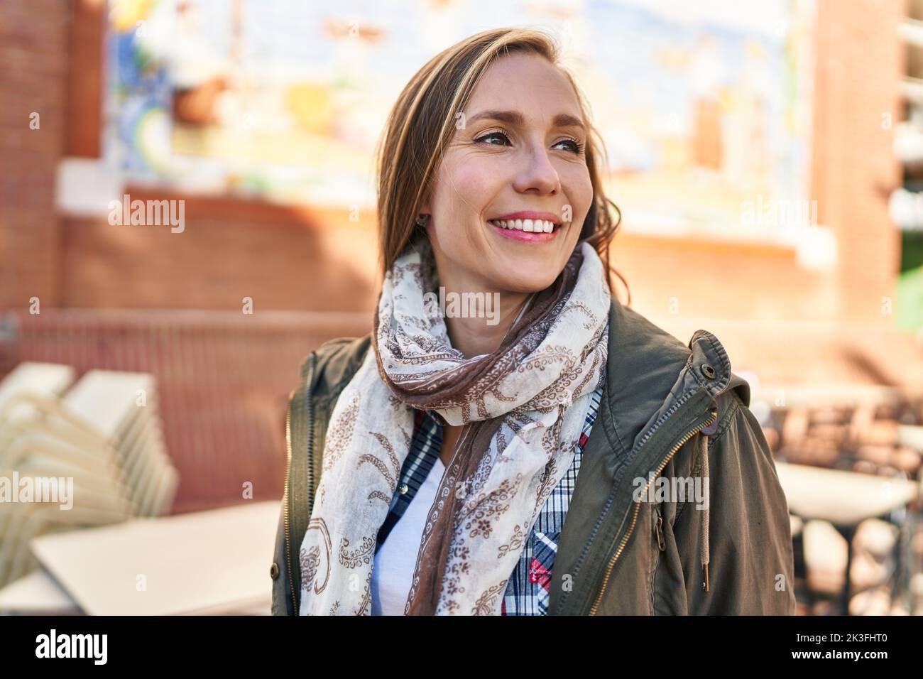 Young blonde woman smiling confident looking to the side at street ...