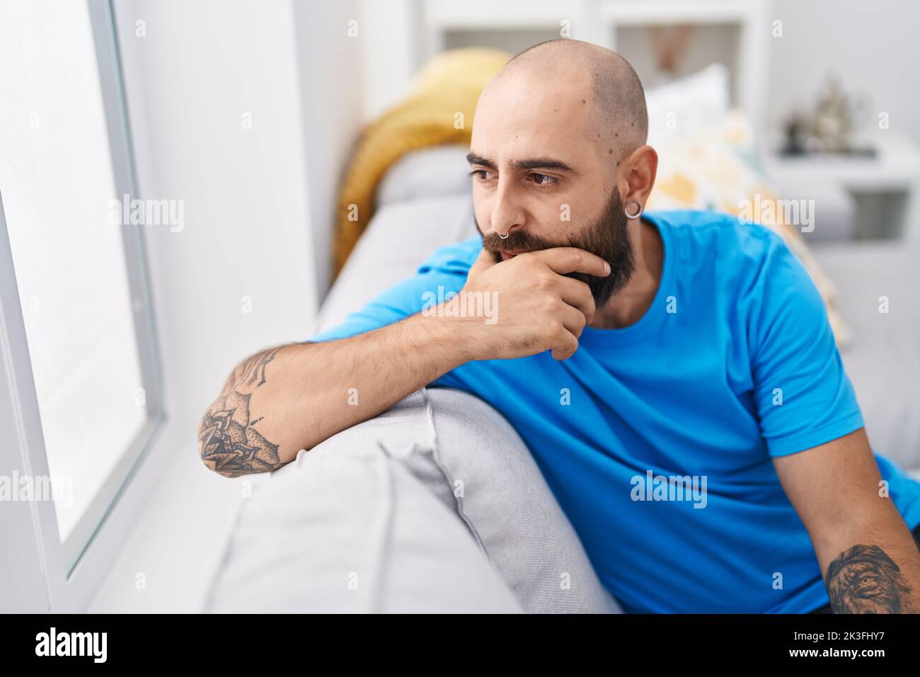 Young bald man sitting on sofa with serious expression at home Stock ...