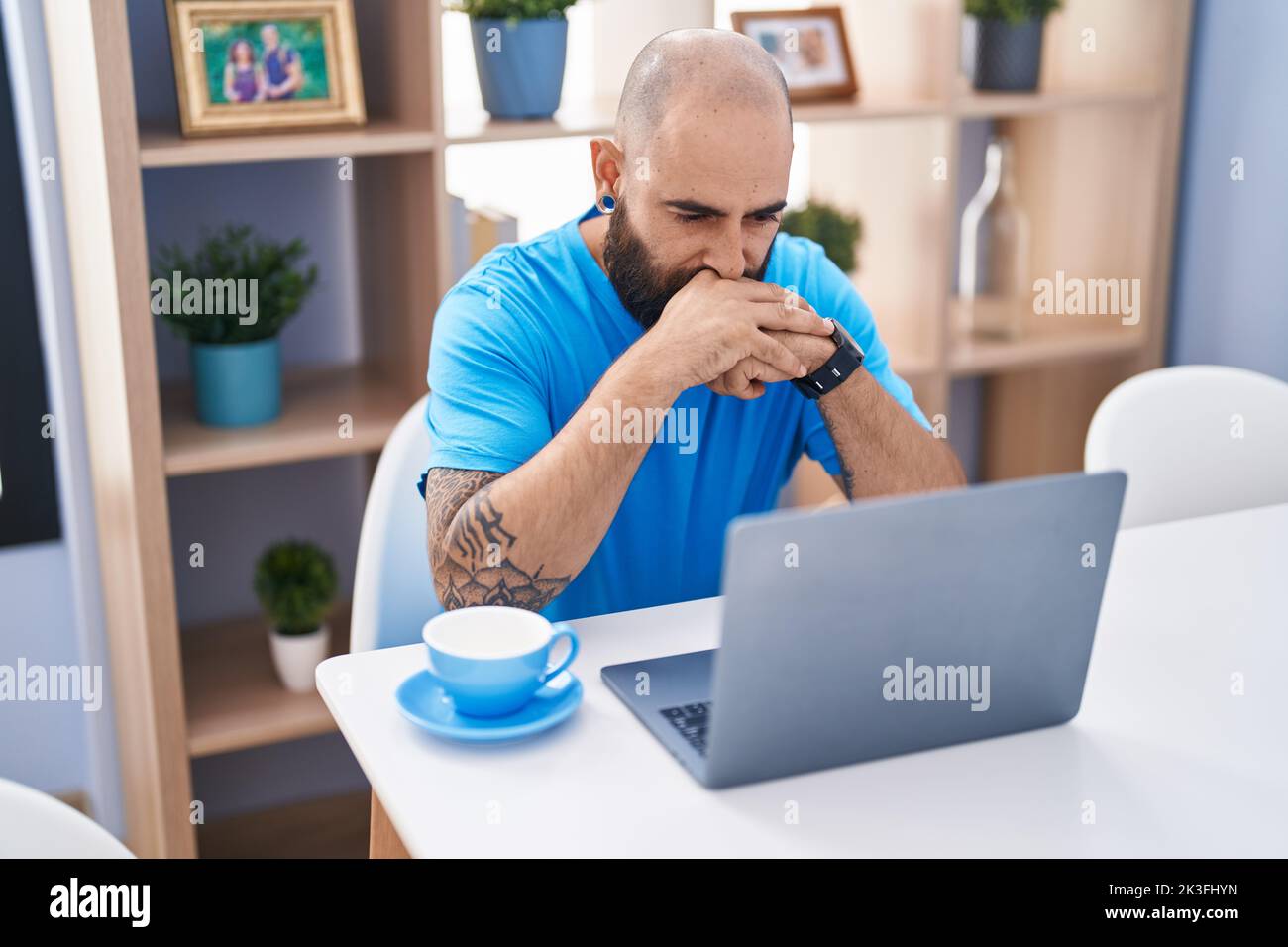 Young bald man using laptop with serious expression at home Stock Photo ...