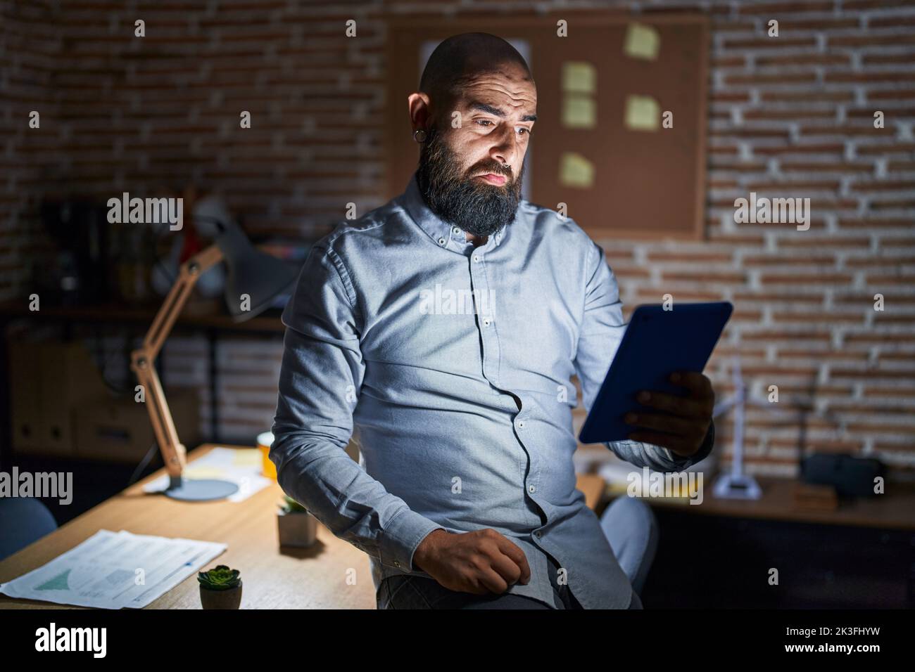 Young hispanic man with beard and tattoos working at the office at ...