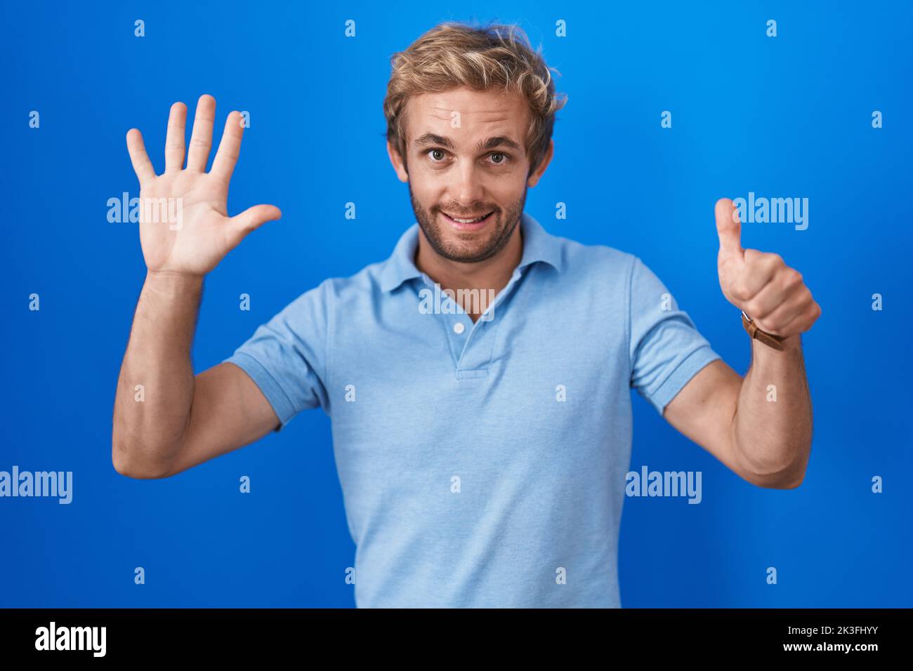 Caucasian man standing over blue background showing and pointing up ...