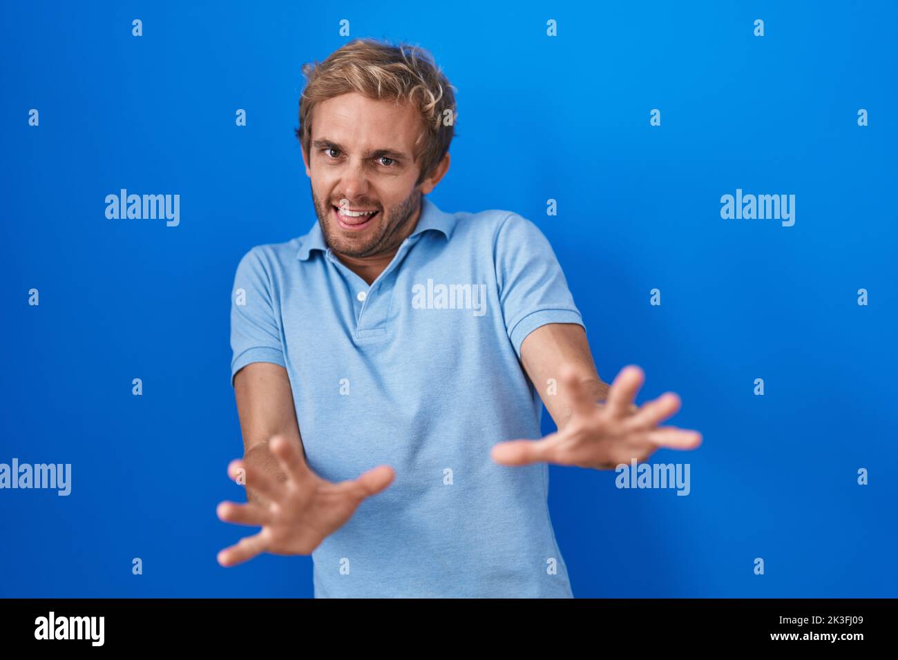 Caucasian man standing over blue background afraid and terrified with ...