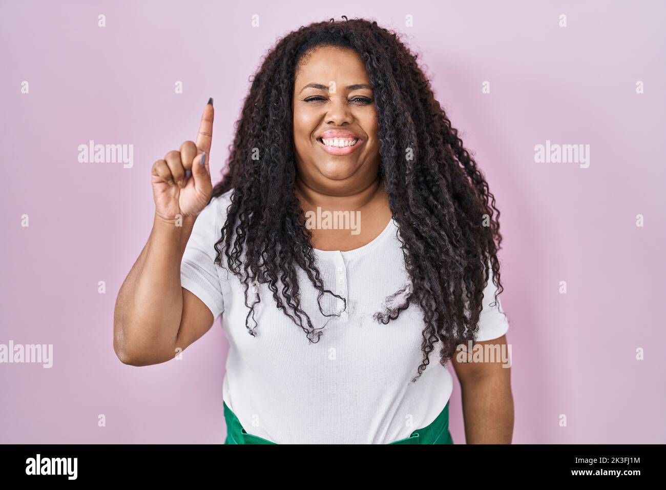 Plus size hispanic woman standing over pink background showing and ...