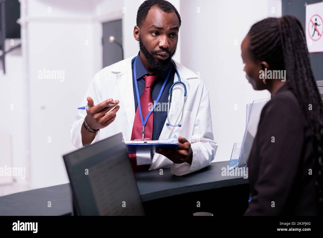 General practitioner talking to receptionist about healthcare insurance ...