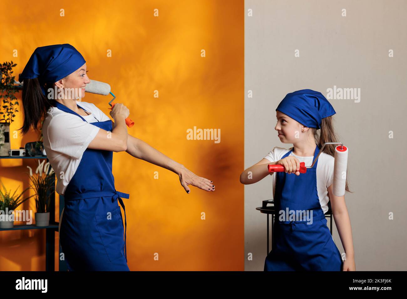 Family having fun with painting tools, using paintbrush roller to paint ...