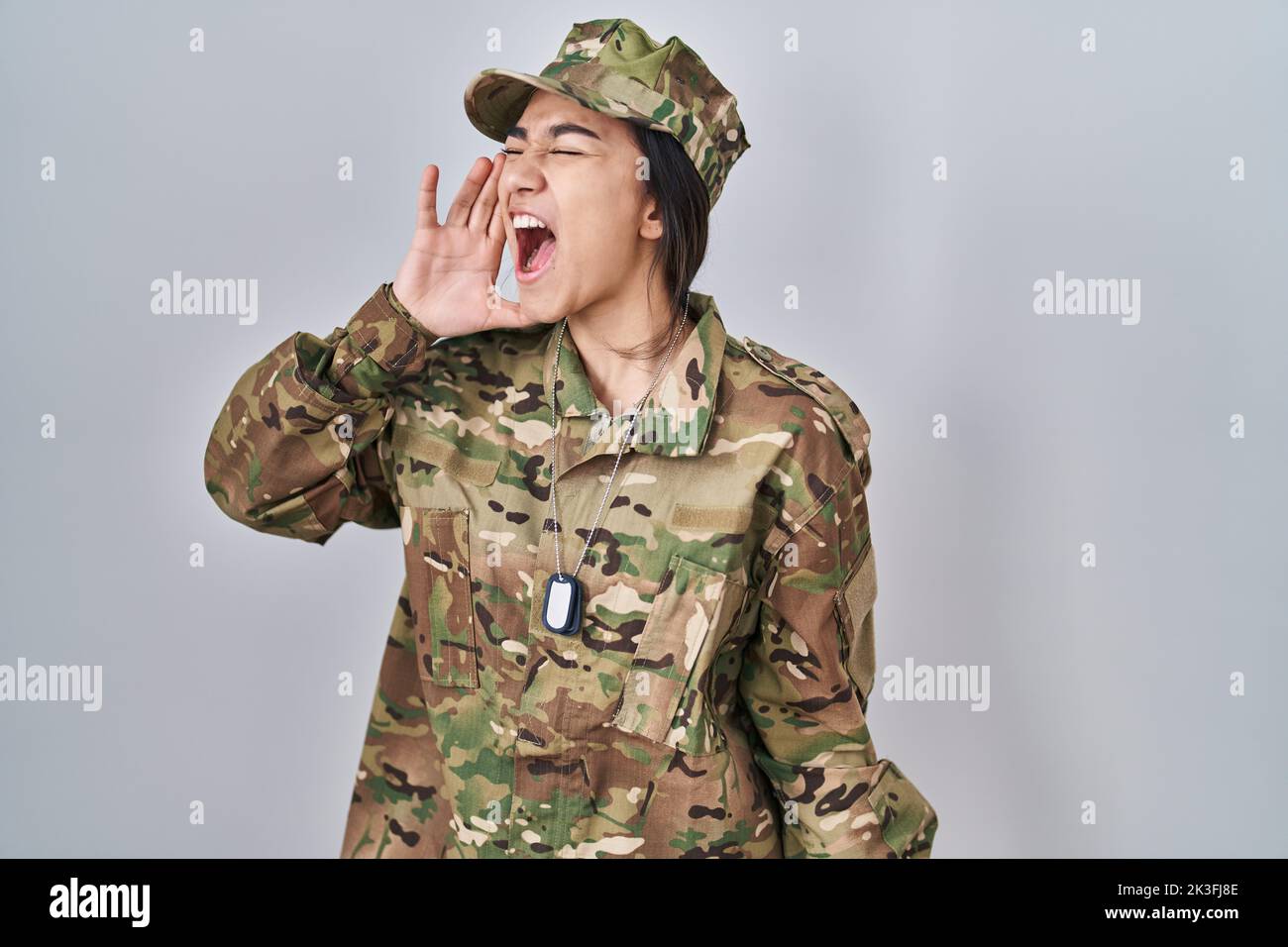Young south asian woman wearing camouflage army uniform shouting and ...