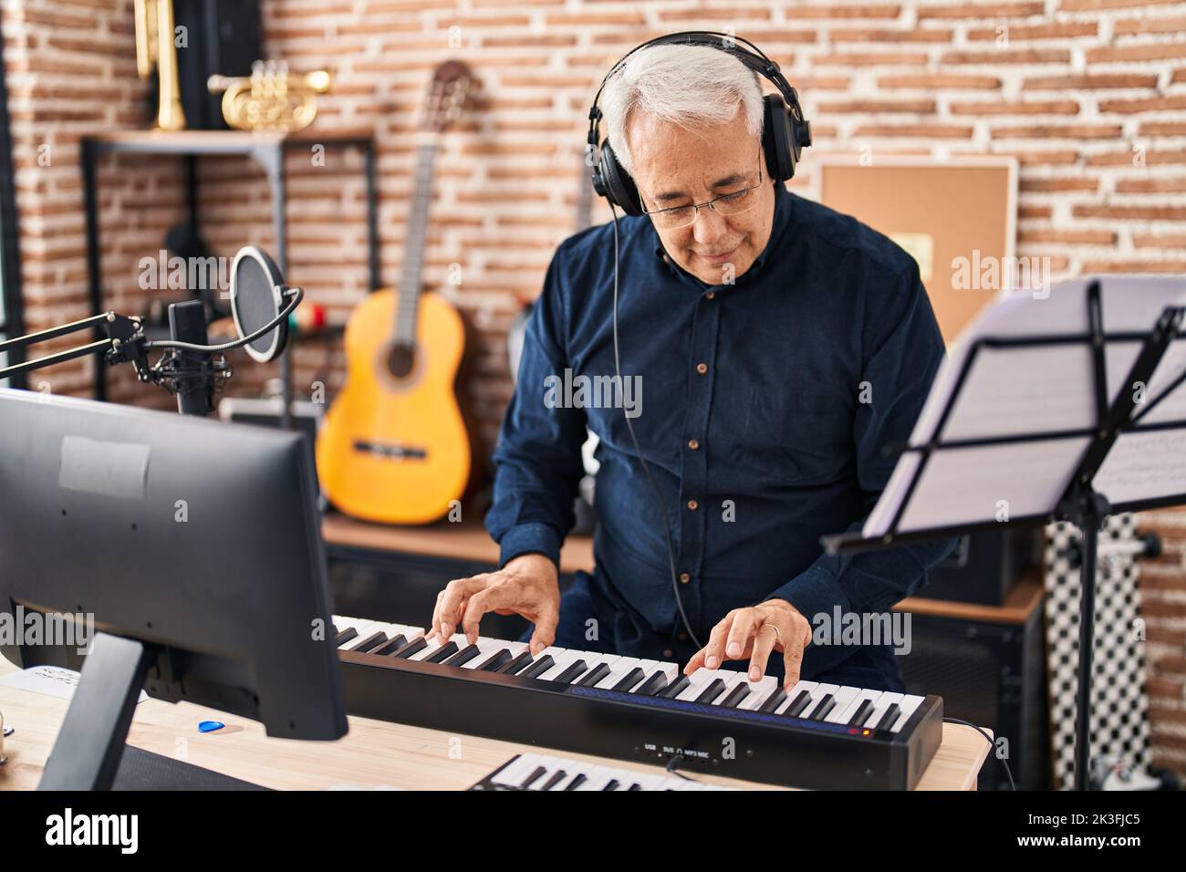 Senior man musician playing piano keyboard at music studio Stock Photo ...