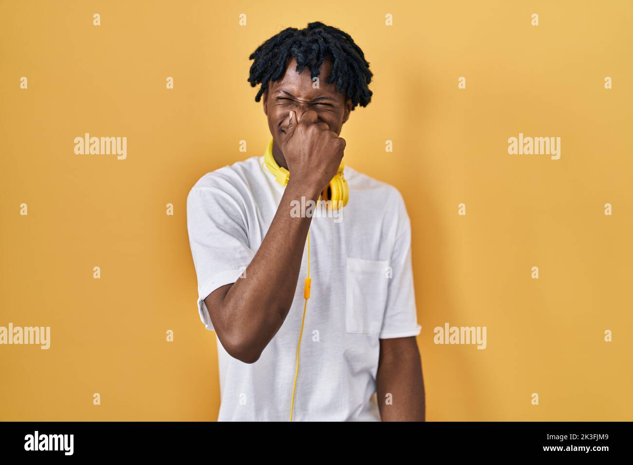 Young african man with dreadlocks standing over yellow background ...