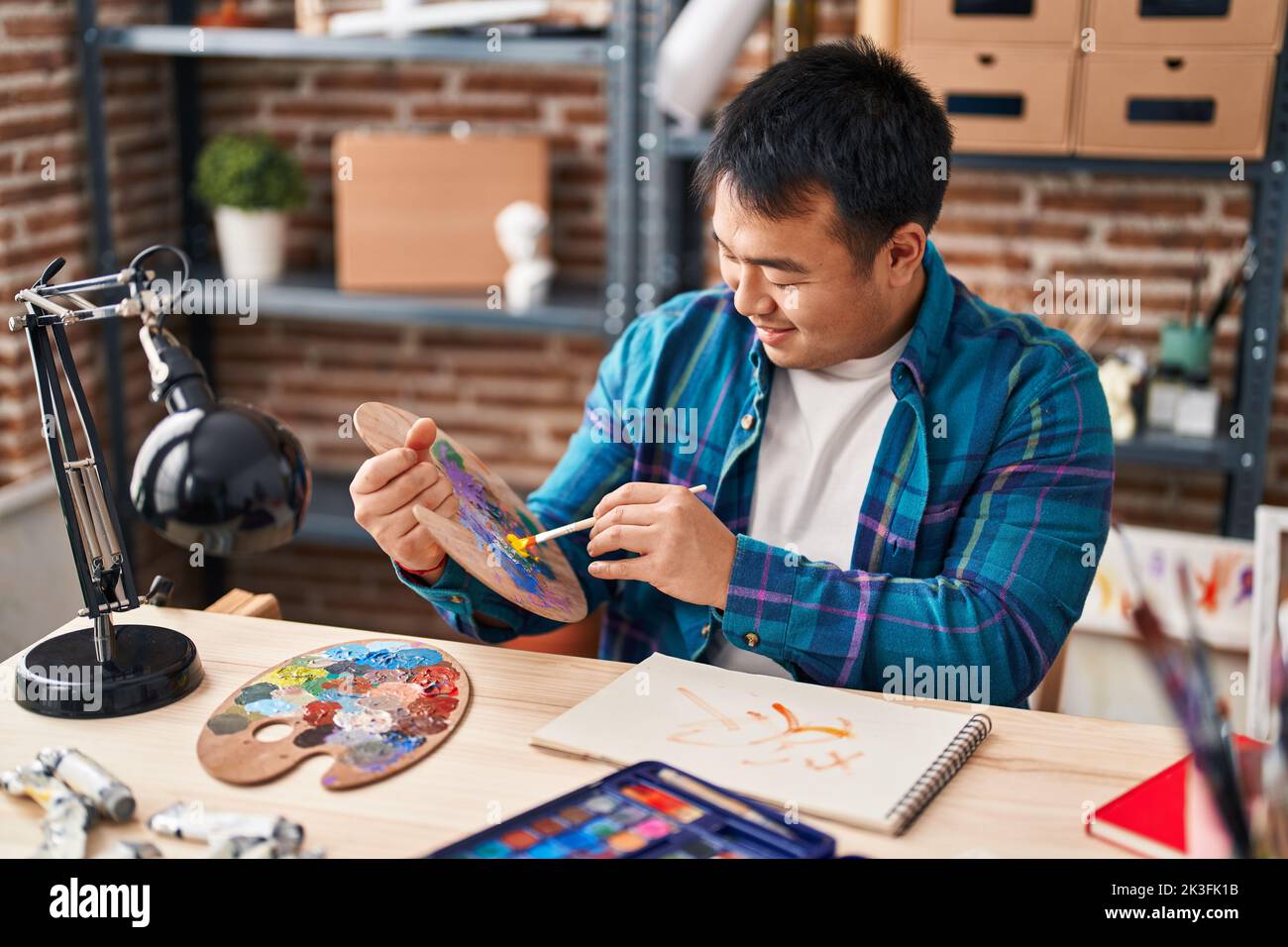 Young chinese man artist drawing on notebook at art studio Stock Photo ...