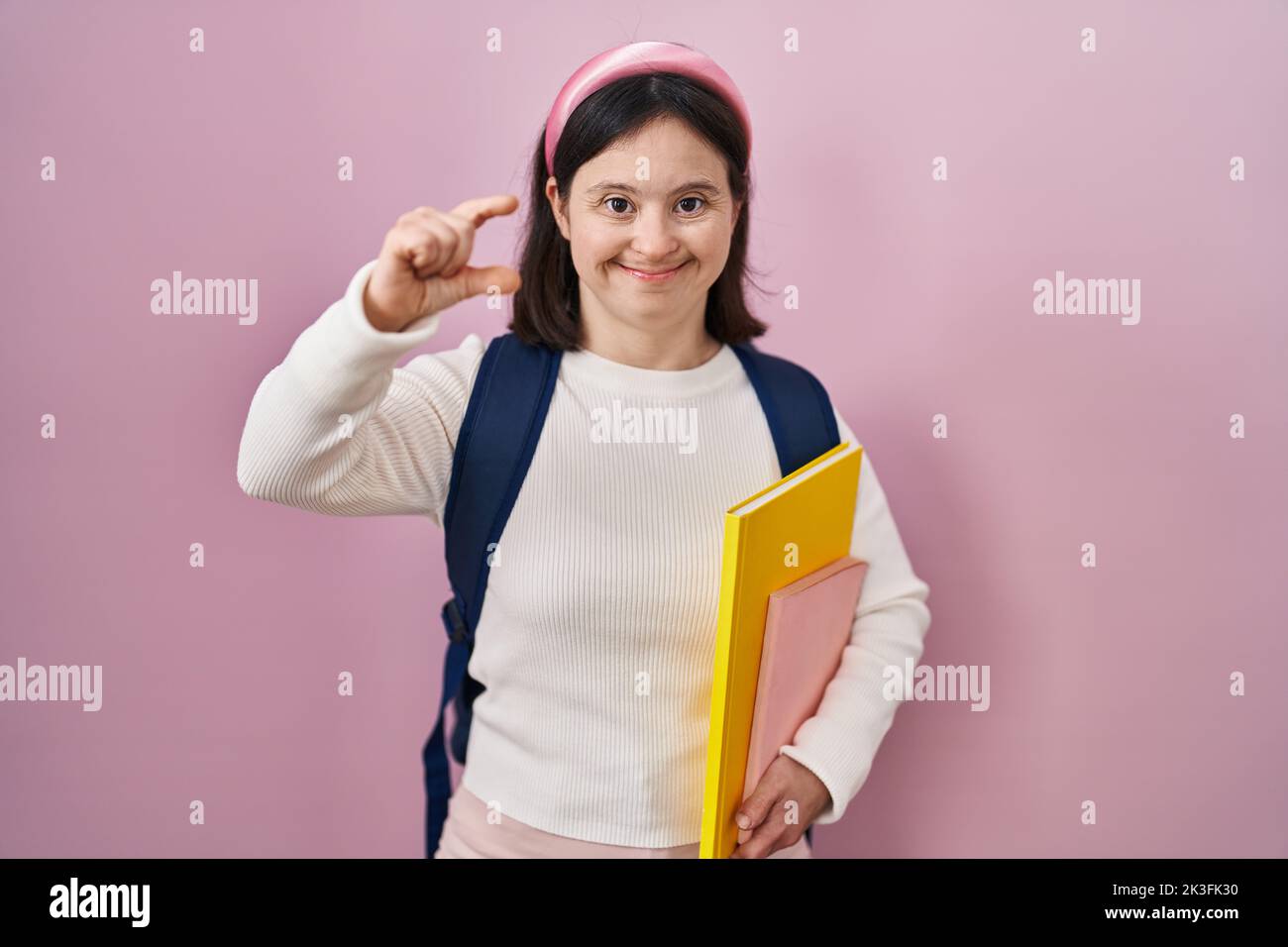 Woman with down syndrome wearing student backpack and holding books ...