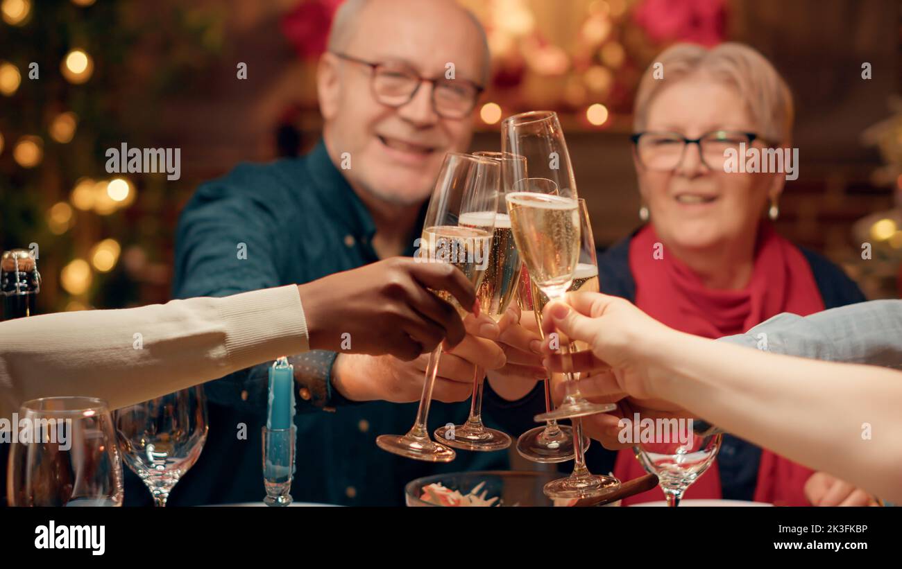 Festive family clinking champagne glasses while enjoying Christmas ...