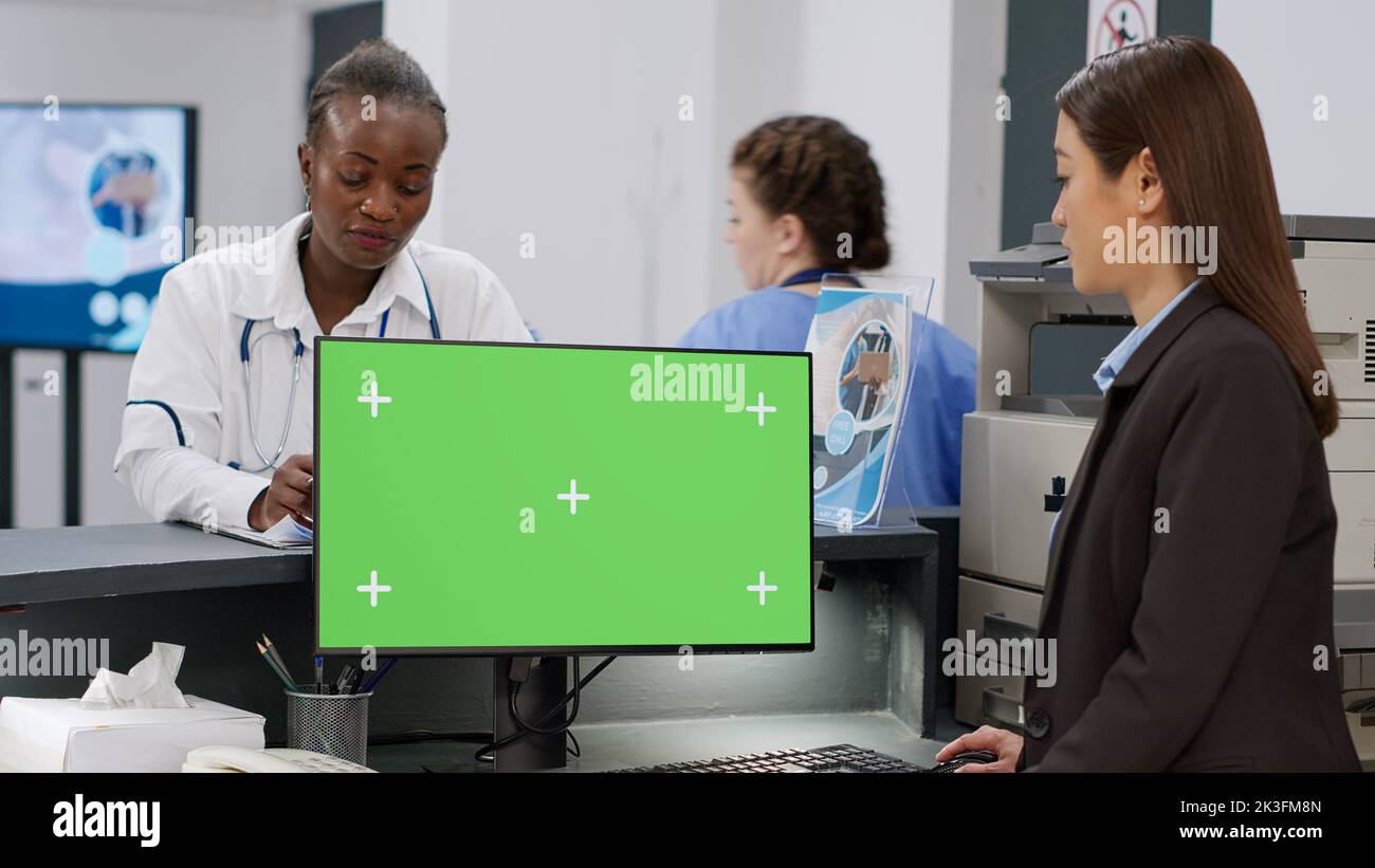 Diverse medical team using computer with greenscreen at reception ...