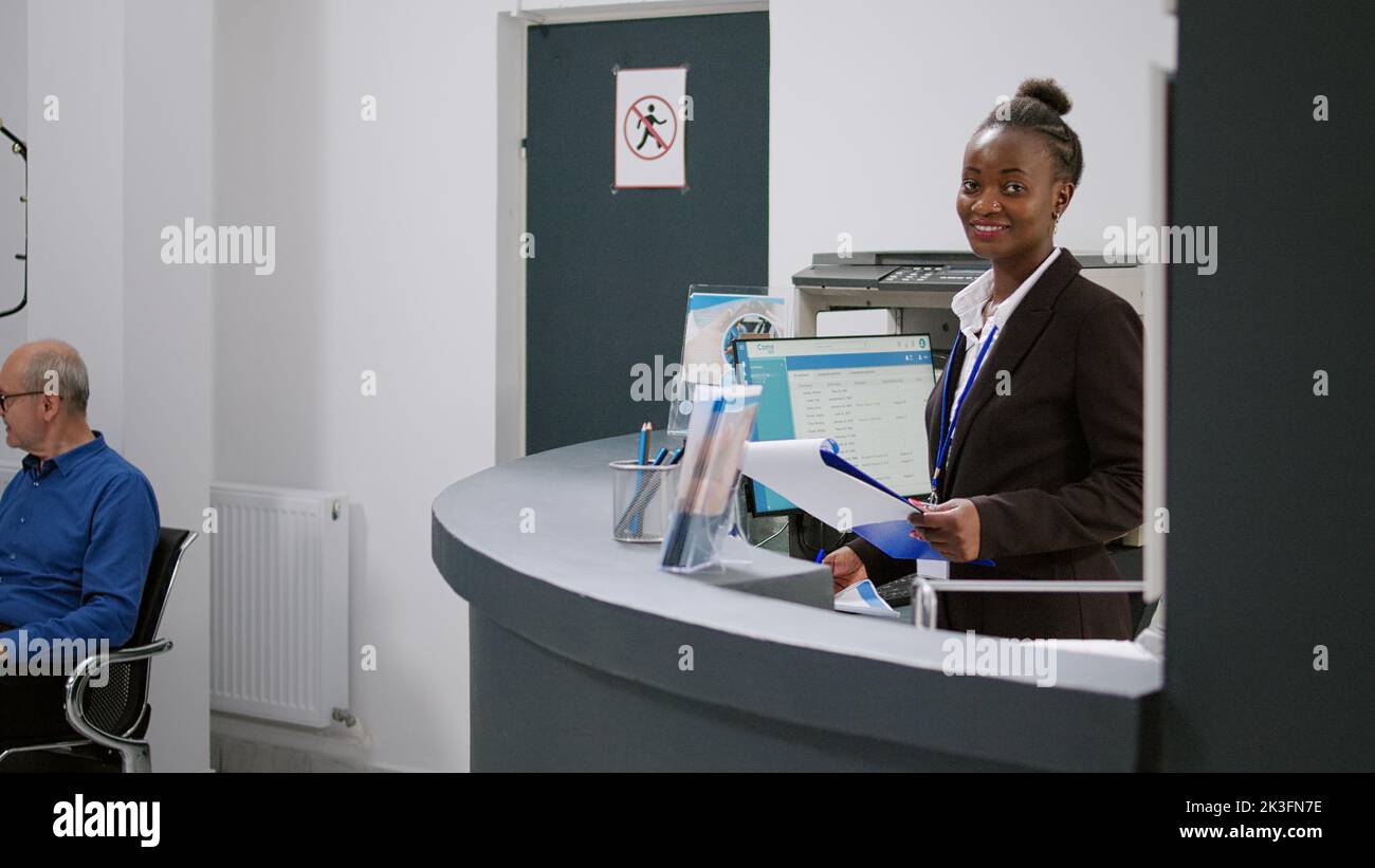 Portrait of african american receptionist working at registration desk ...