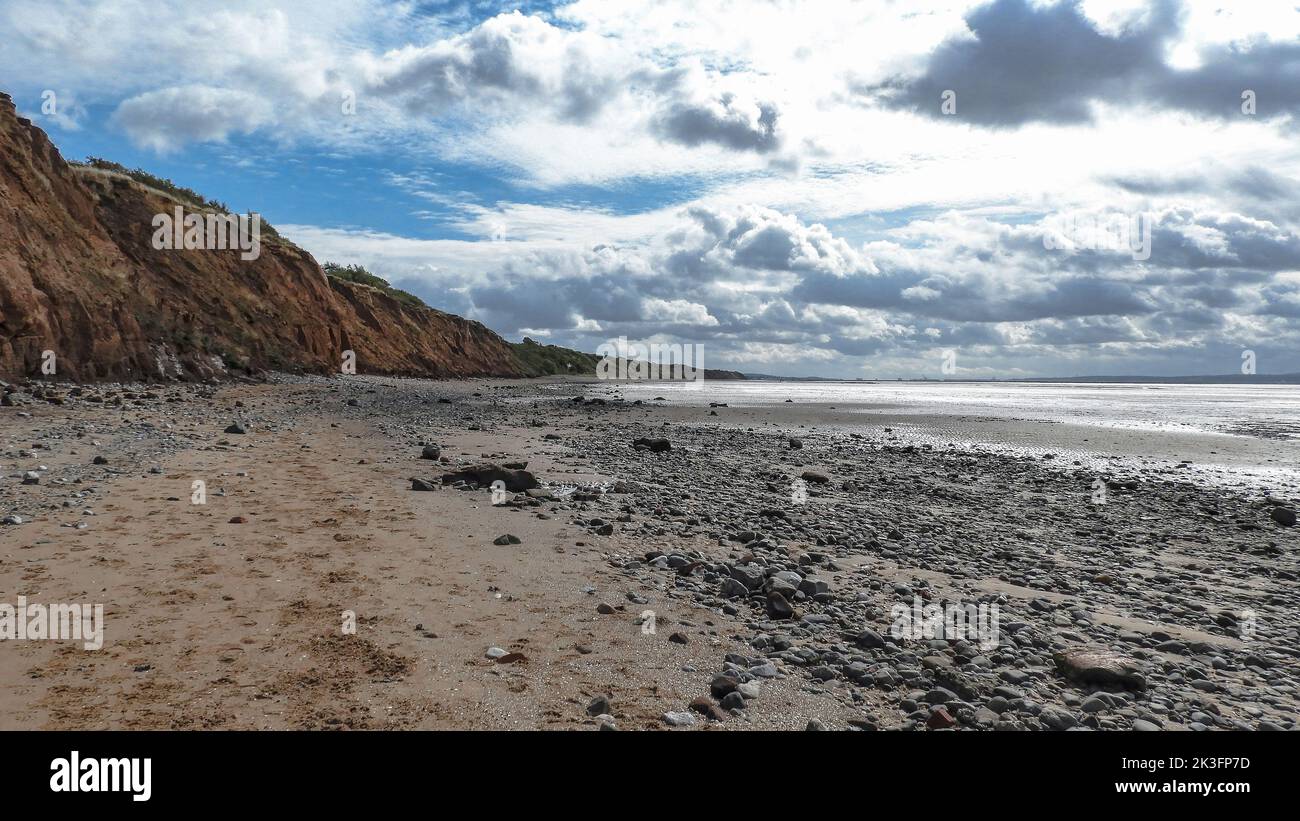 Sandy beach at low tide with dark cliffs and a stormy sky Stock Photo ...