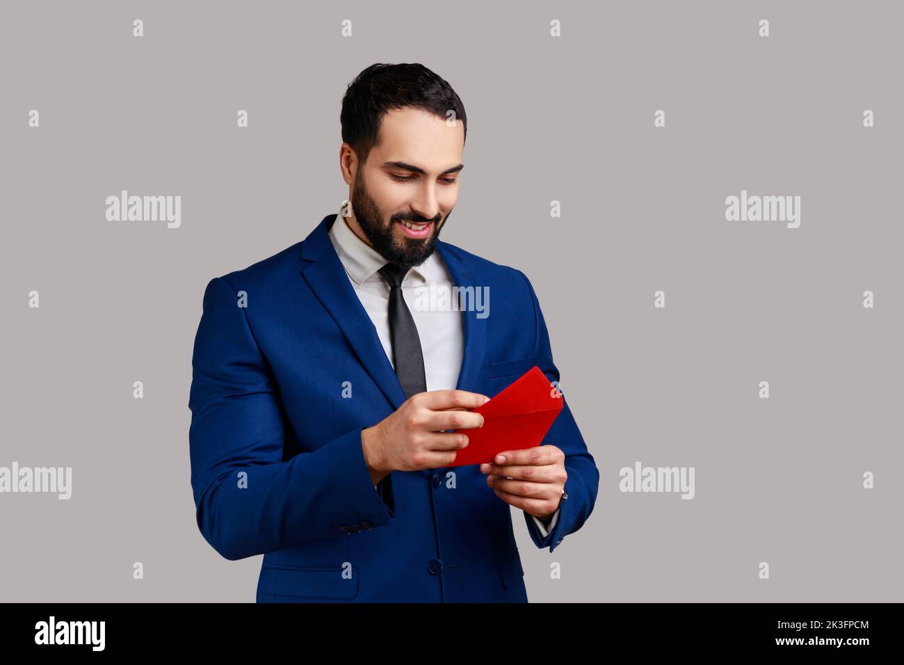 Handsome bearded businessman pulling letter from red envelope, holding ...