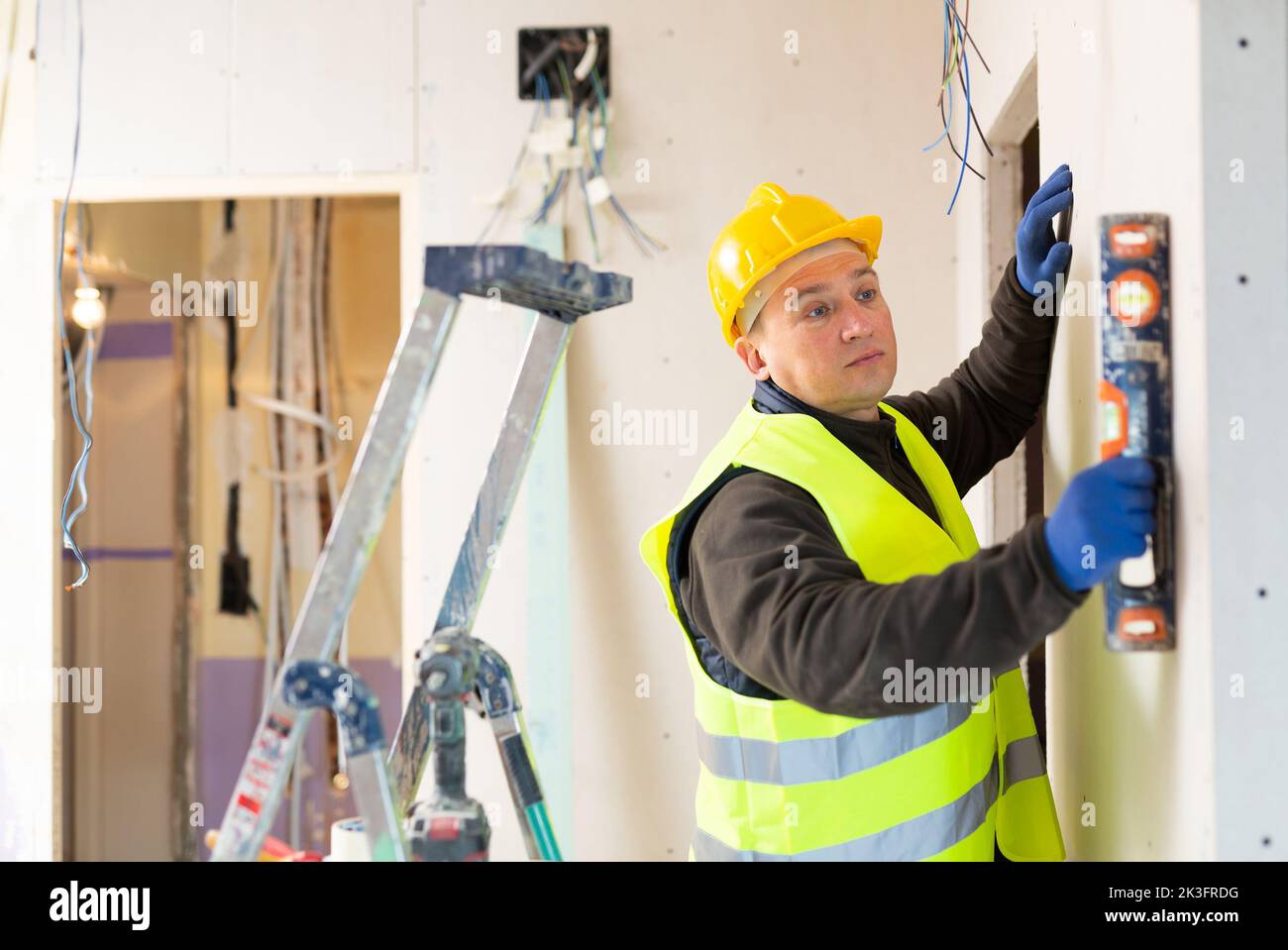 Builder checks the vertical of the wall using level Stock Photo - Alamy