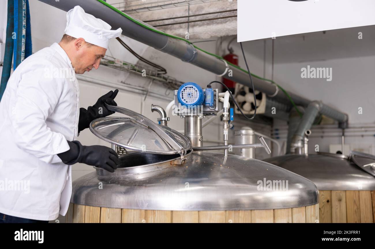 Brewmaster opening lid of fermenter while checking beer production ...