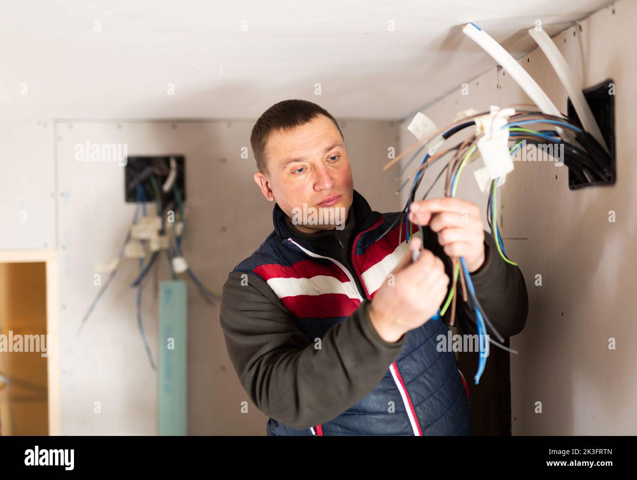 Professional builder engaged in electrical installation work at indoors ...