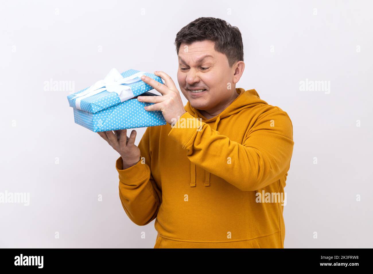 Portrait of middle aged man opening gift box and peeping inside with ...