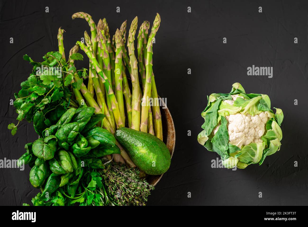 Various green vegetables on a black background. Cauliflower, avocado ...