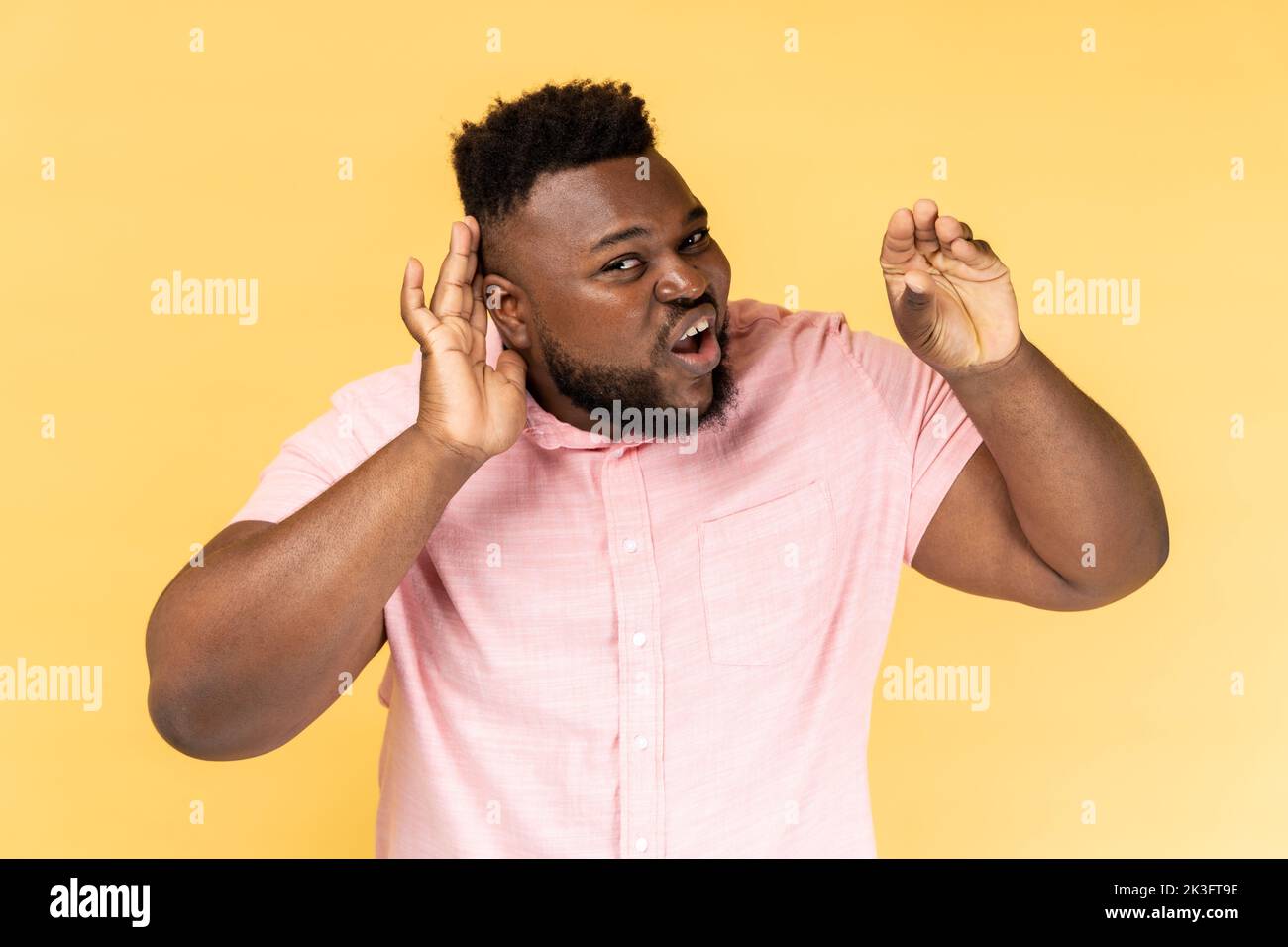Portrait of unsure bearded young adult man wearing pink shirt standing ...