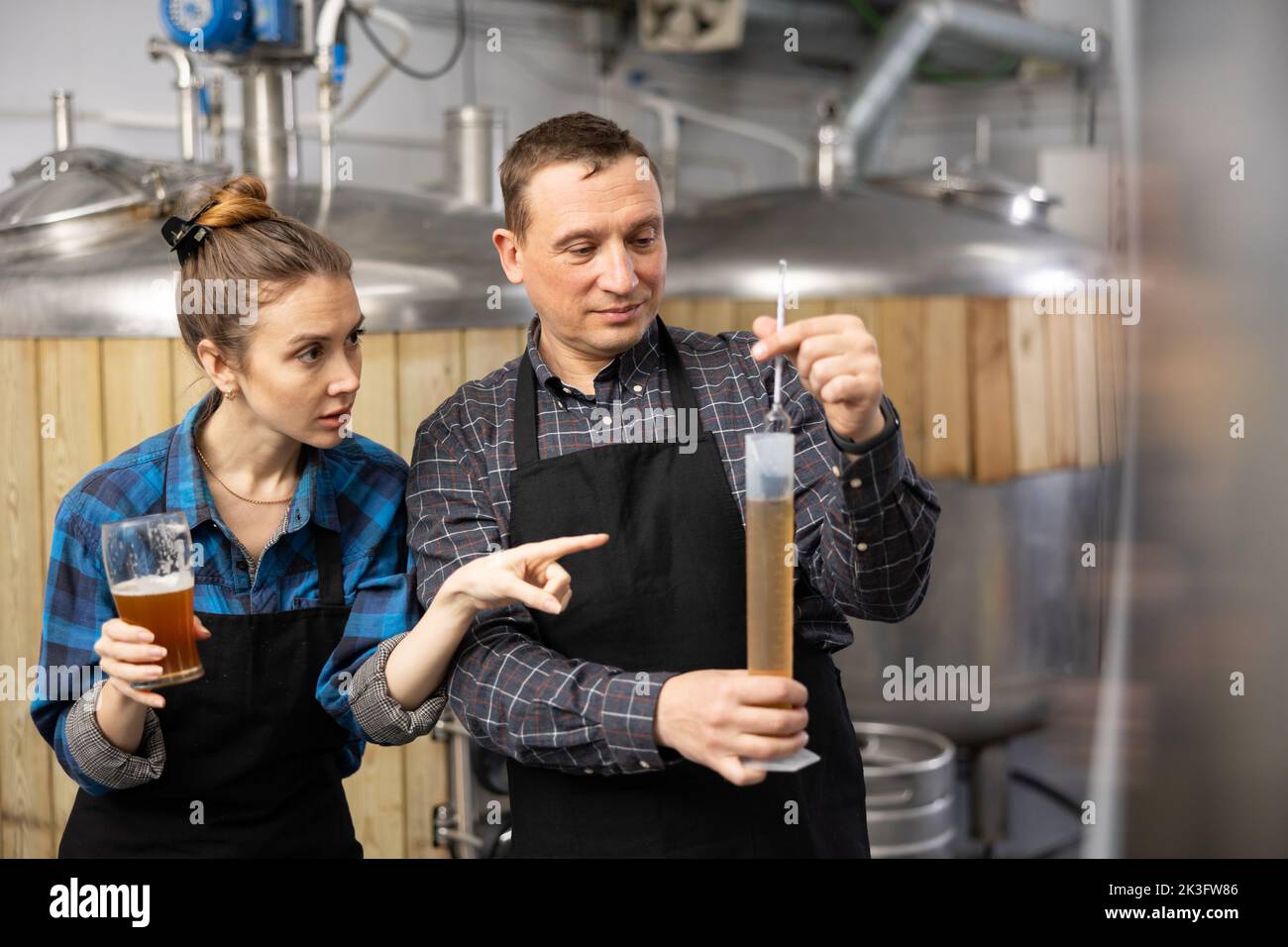 Man and woman brewmasters measuring beer with alcoholometer Stock Photo ...