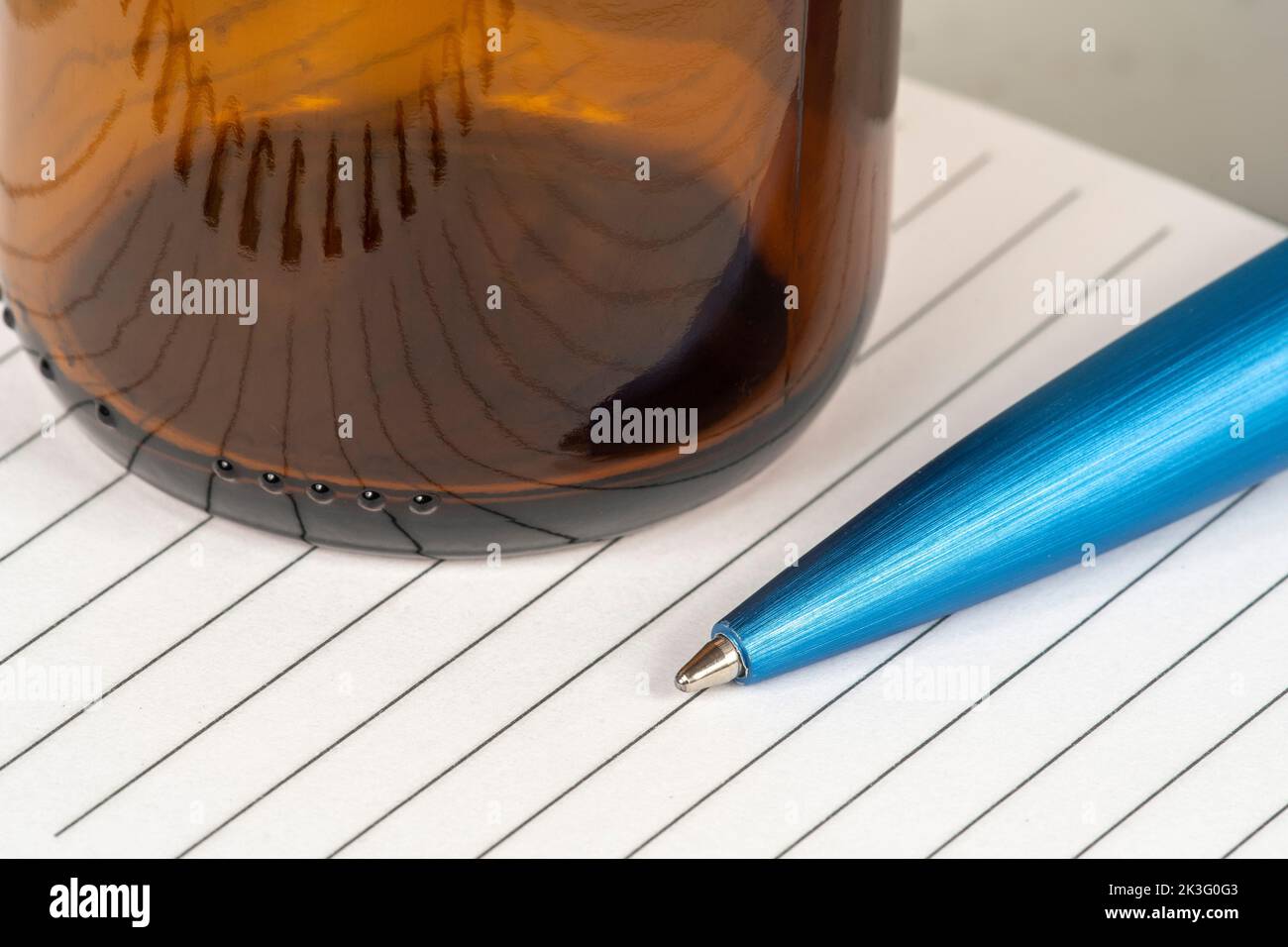 ballpoint pen on lined paper pad with empty amber glass Stock Photo - Alamy