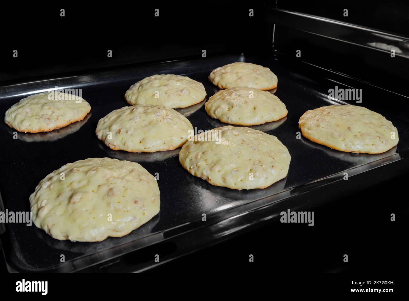 Cooking eight crunchy oatmeal cookies on metal sheet in oven Stock ...