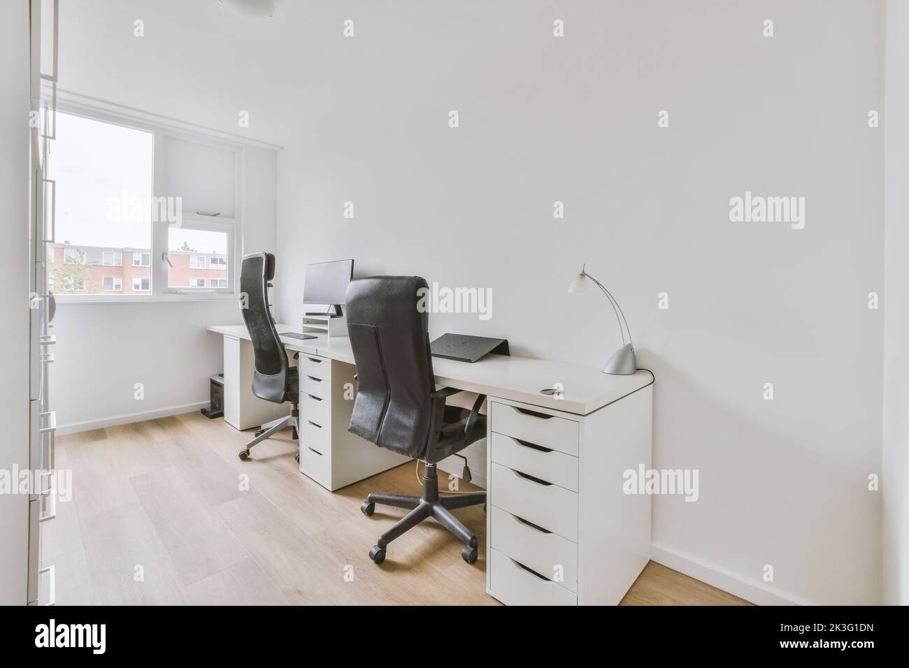Comfortable chair placed near desk with computer monitors and ...
