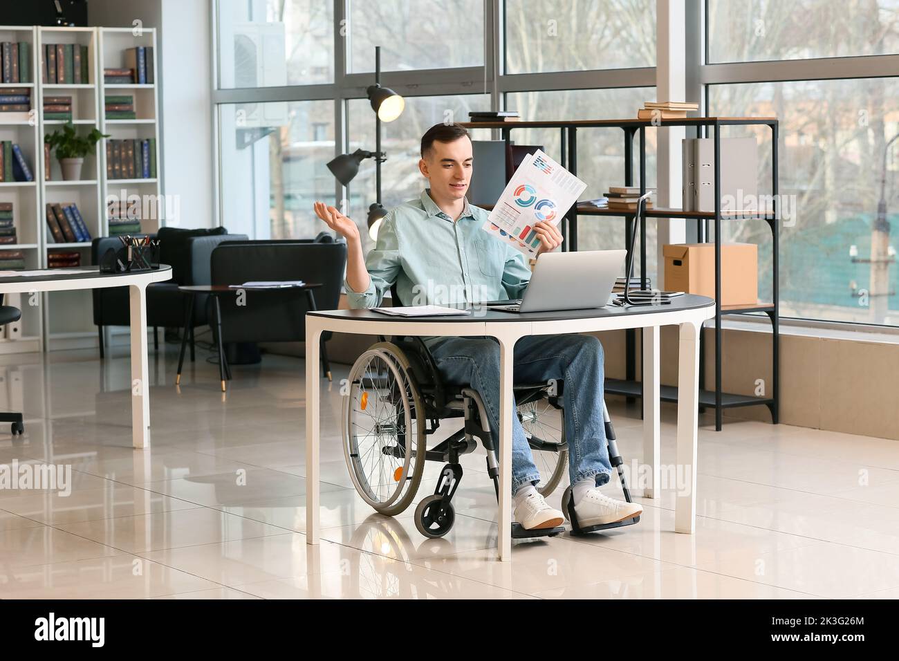 Young man in wheelchair working in office Stock Photo - Alamy