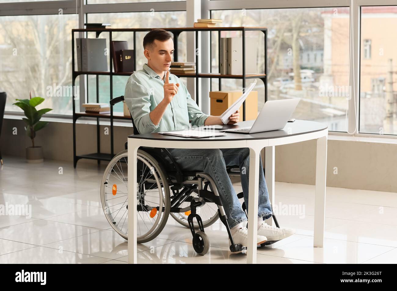 Young man in wheelchair working in office Stock Photo - Alamy