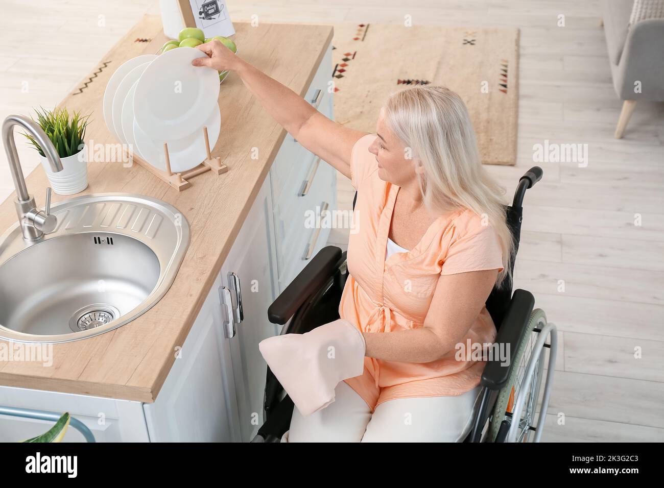 Mature woman with physical disability washing dishes in kitchen Stock ...