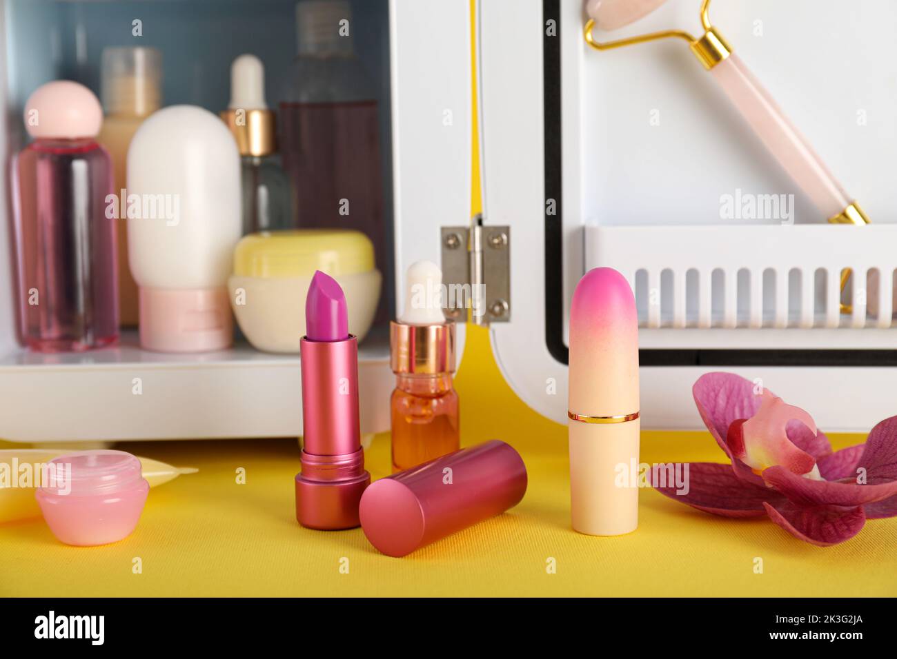 Cosmetic refrigerator with makeup products and flower on yellow ...