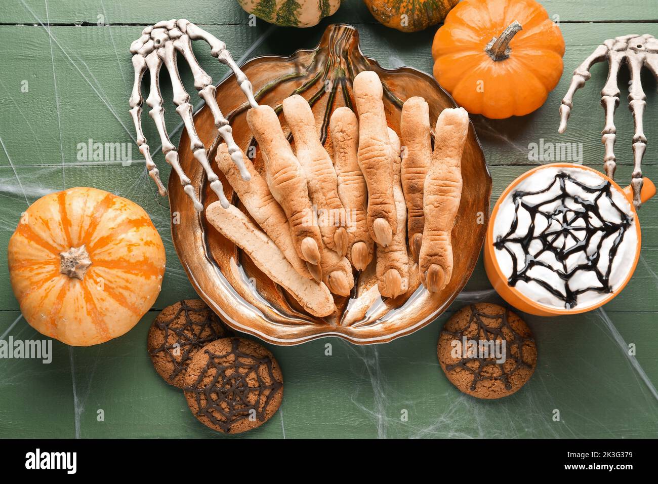 Plate with Halloween cookies, skeleton hands, drink and pumpkins on ...