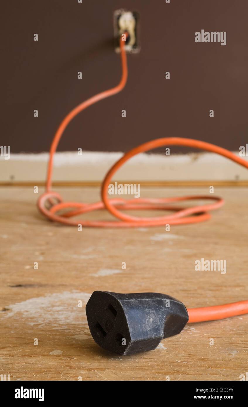 Orange electrical extension cord on plywood floor inside home Stock ...