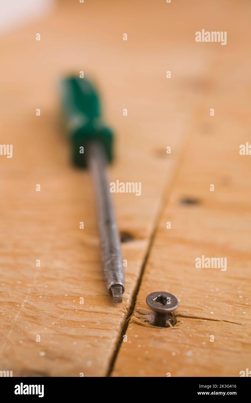 Green screwdriver with square tip and metal screw head sticking out ...