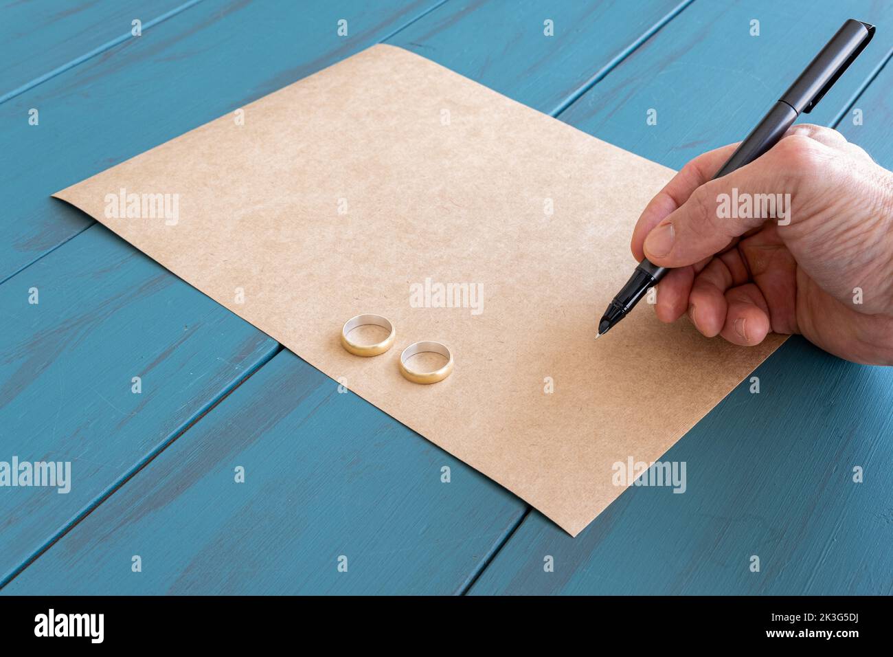 Man with fountain pen ready to sign on brown paper. Next to wedding ...